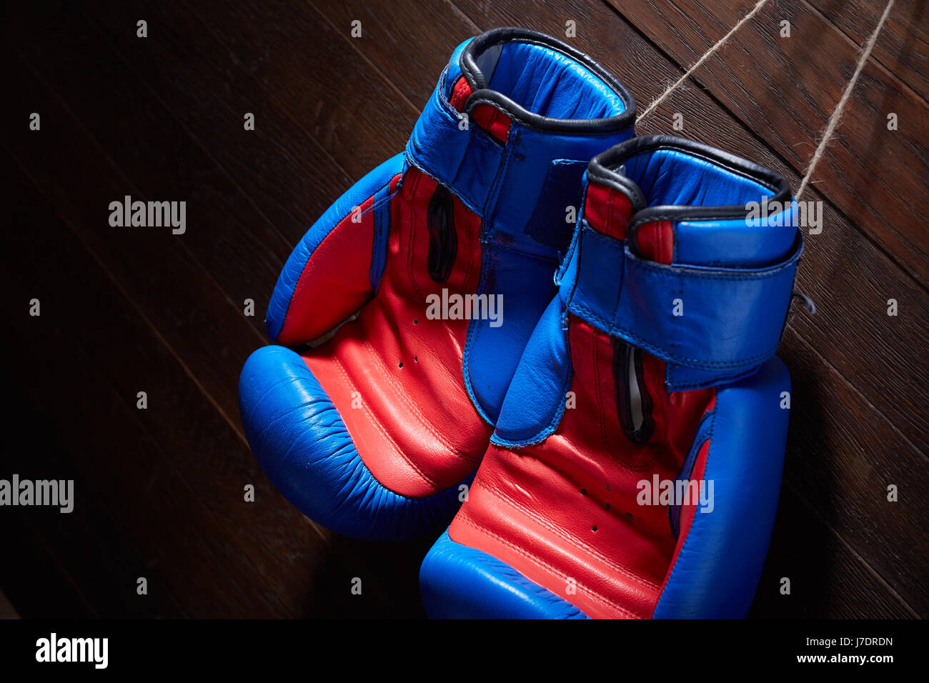 Close-up of the pair of blue and red boxing gloves hanging in a wooden ...