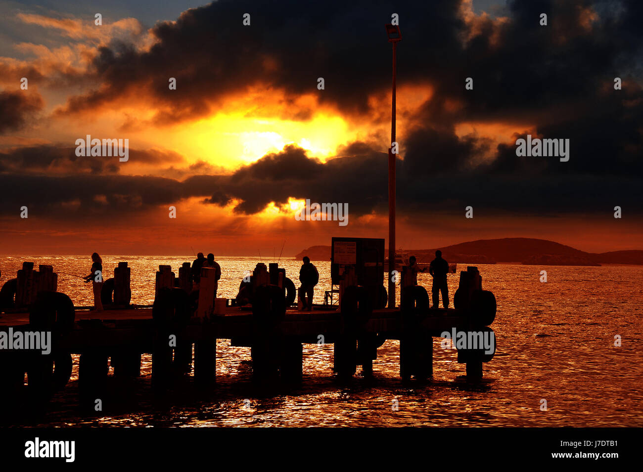 Silhouetted people on a jetty fishing in Cervantes, Western Australia ...