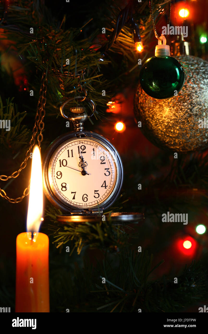 Vintage pocket watch hanging on Christmas tree near lighting candle ...