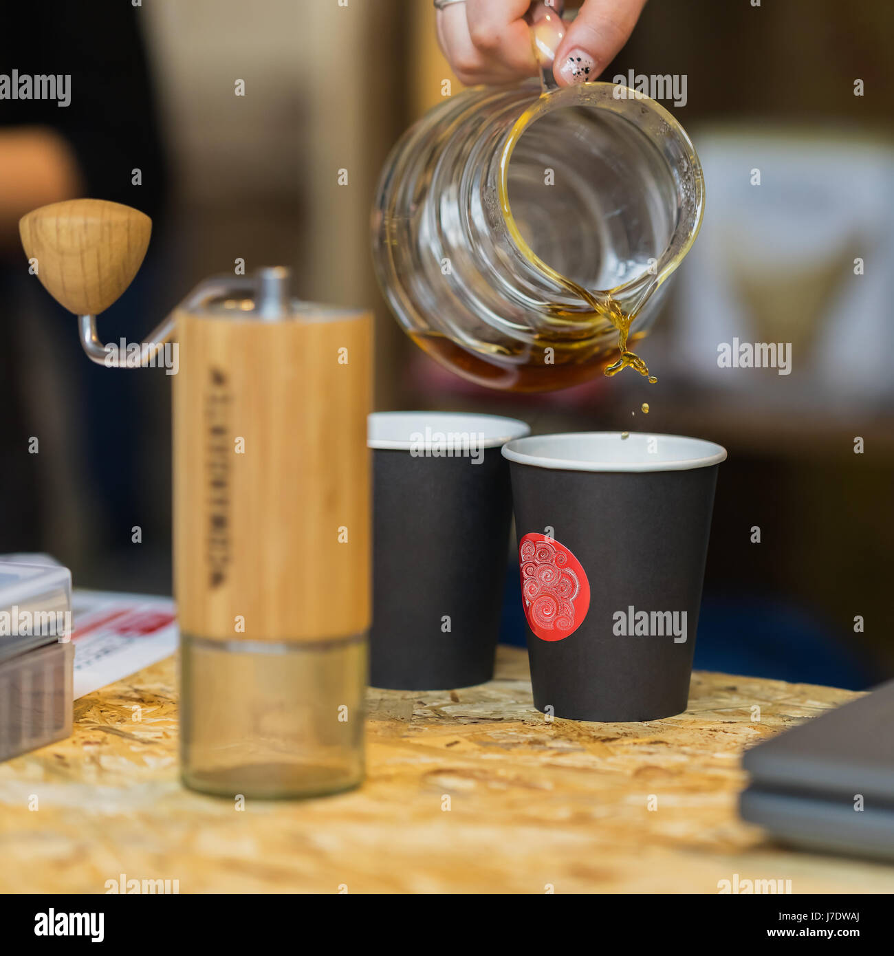 Hand of a barista girl pouring filtered coffee into paper cup, abstract ...
