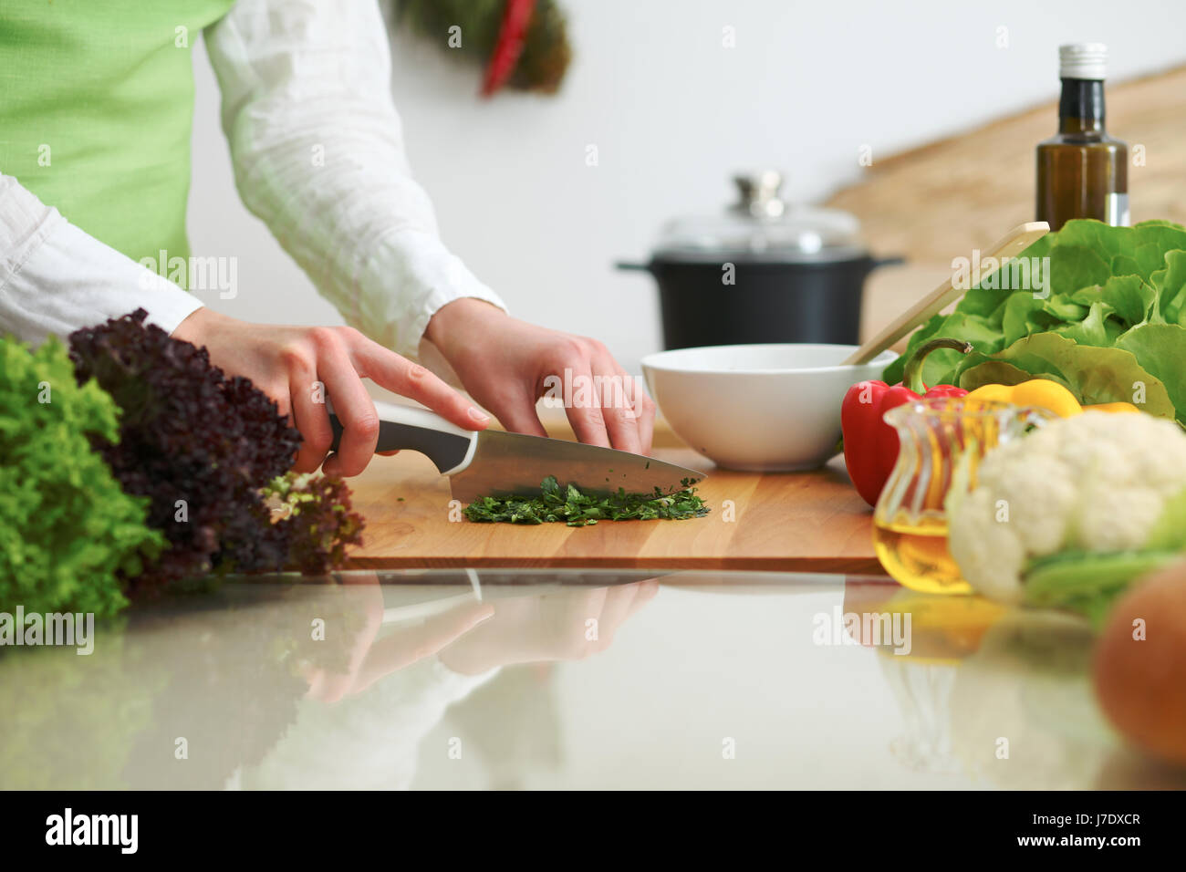 Closeup of human hands cooking vegetables salad in kitchen on the glass ...