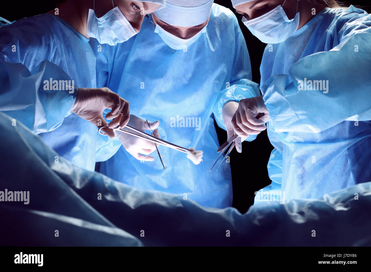 Group of surgeons at work in operating theater toned in blue Stock ...