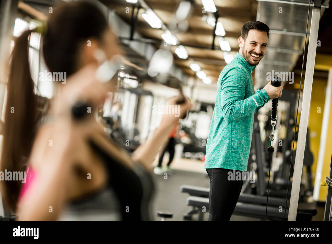 Active female weightlifting in sports club with her coach consulting ...