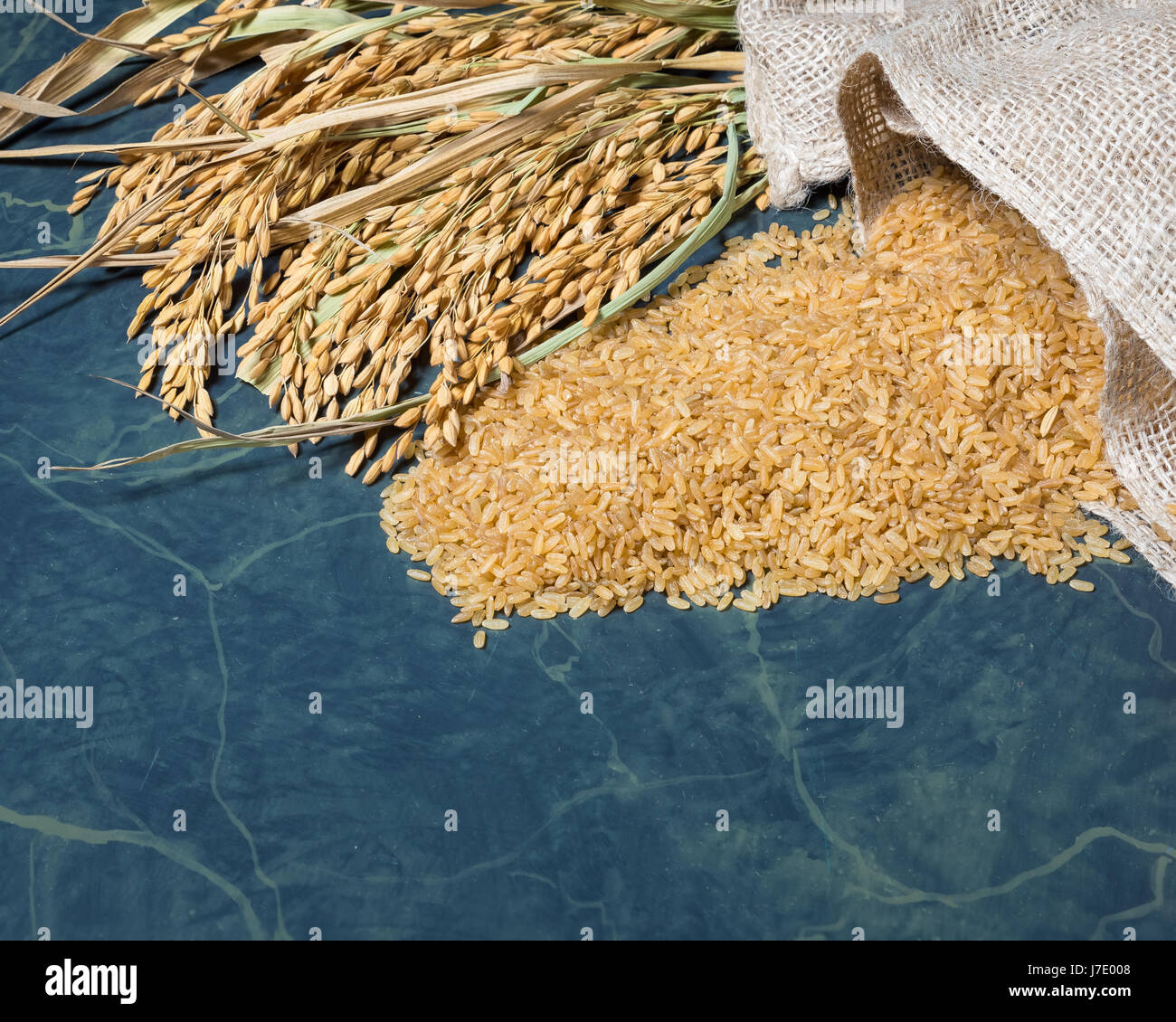 Brown rice uncooked in a bag with a pile of brown rice and spike rice ...