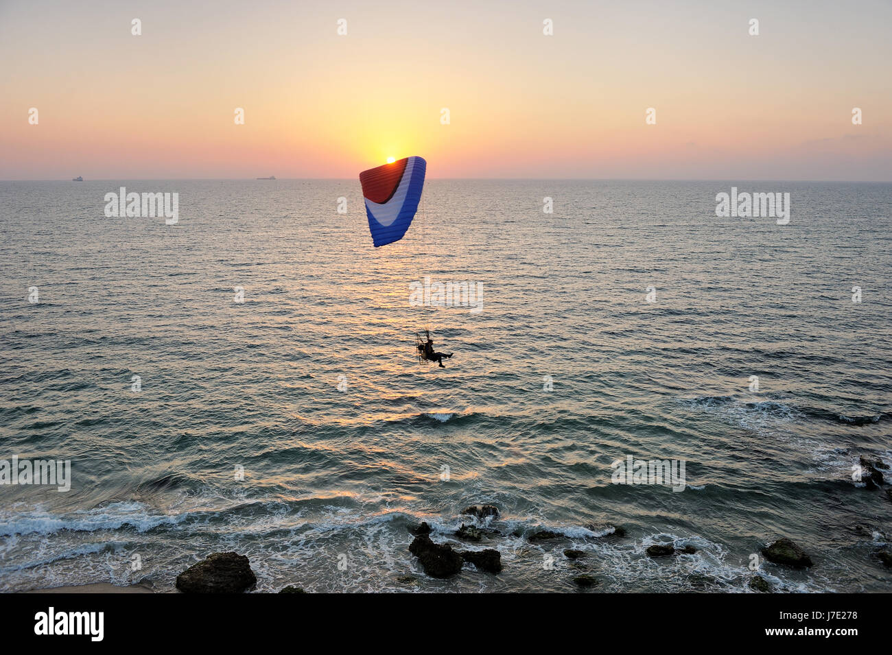 Powered paraglider flying over the sea at sunset sky background Stock ...