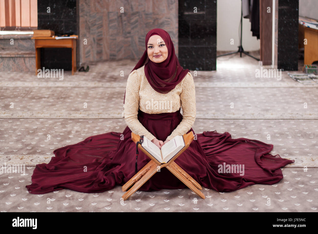 Young and beautiful girl sitting covered in sumptuous dress and teaches ...