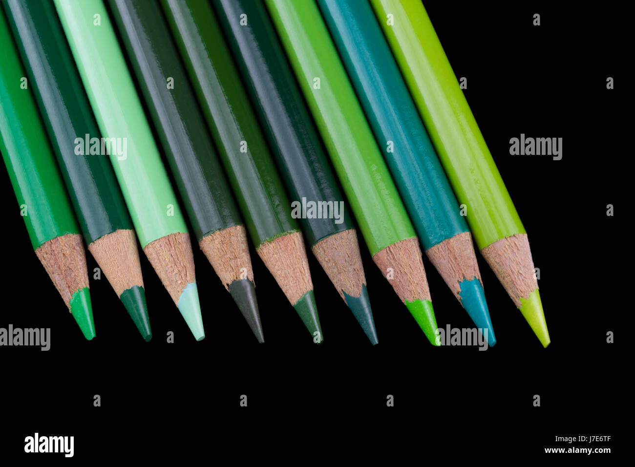 Nine green pencils of various hues and shades, lined up and isolated ...