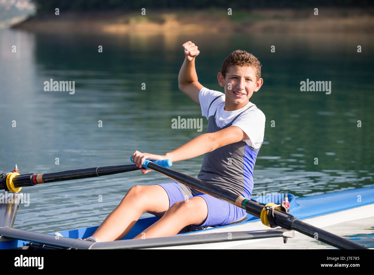 A Young single scull rowing competitor paddles on the tranquil lake ...