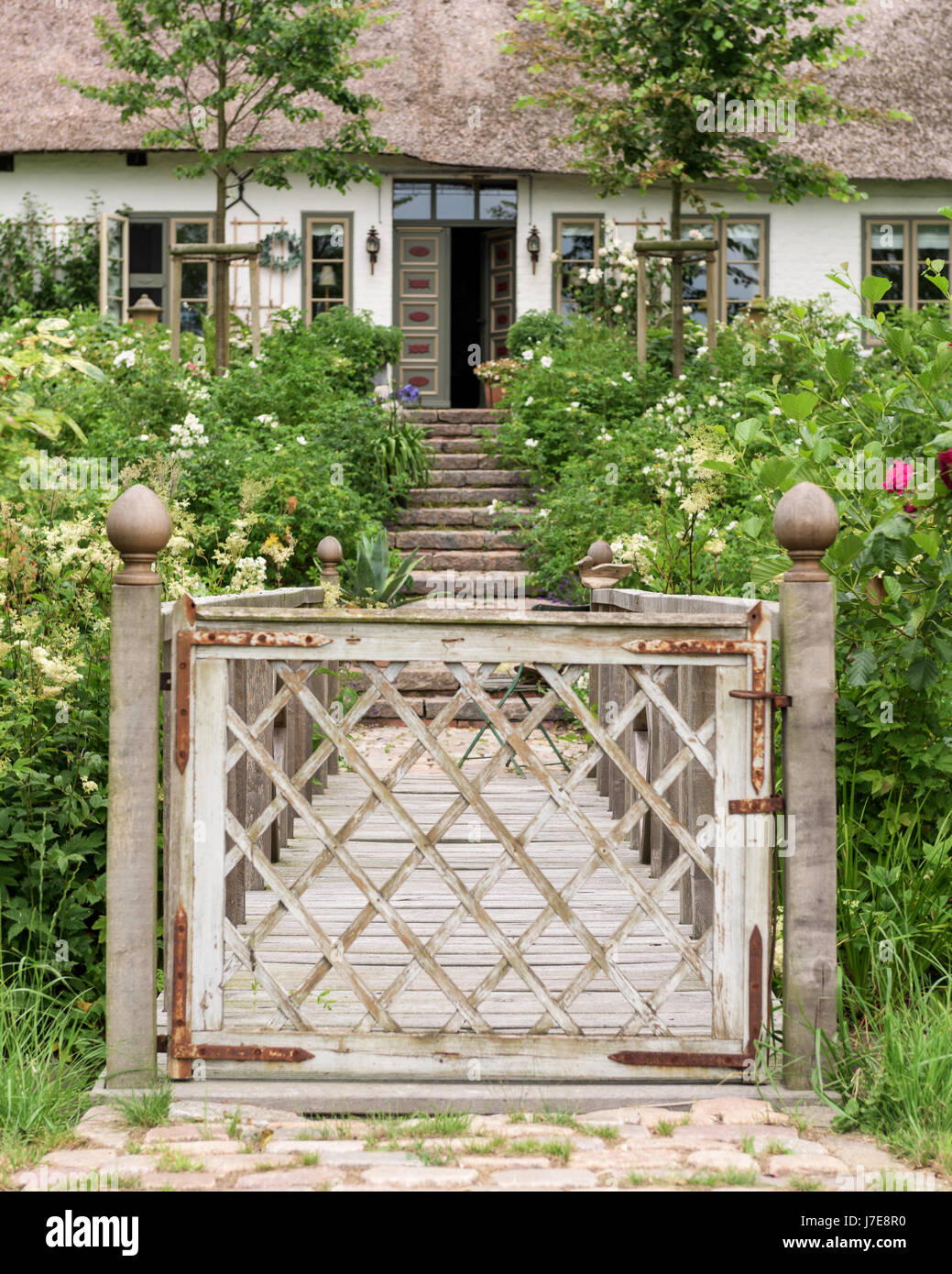 Gated footbridge and garden of thatched 17th century famhouse built on ...