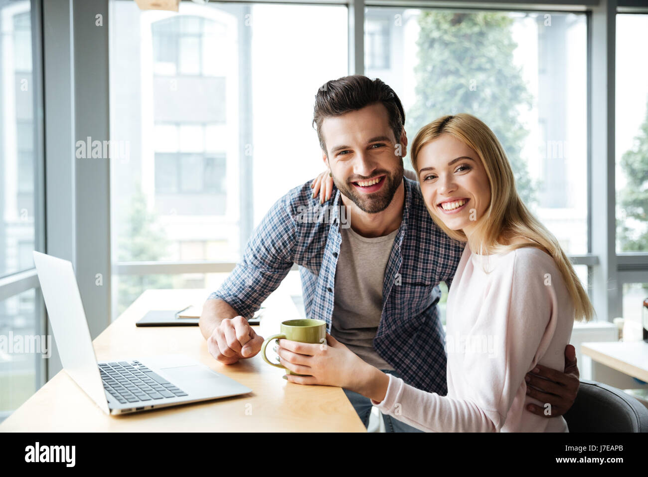 Photo of young two happy colleagues in office coworking while using ...