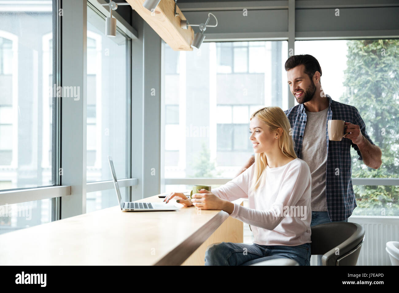 Two cheerful colleagues in office coworking while using laptop computer ...