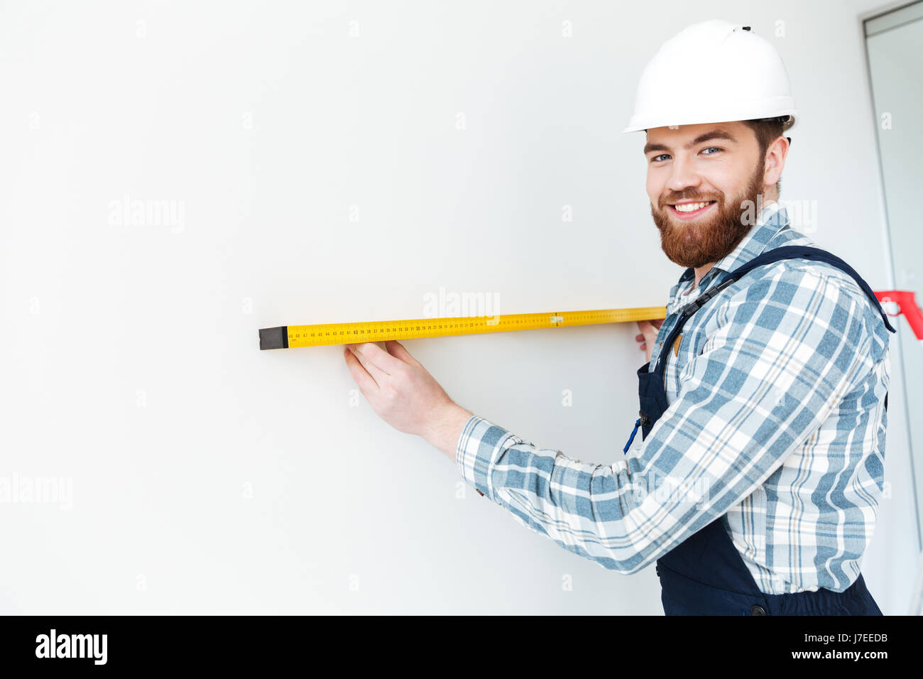 Young positive man holding ruler and looking camera isolated Stock ...