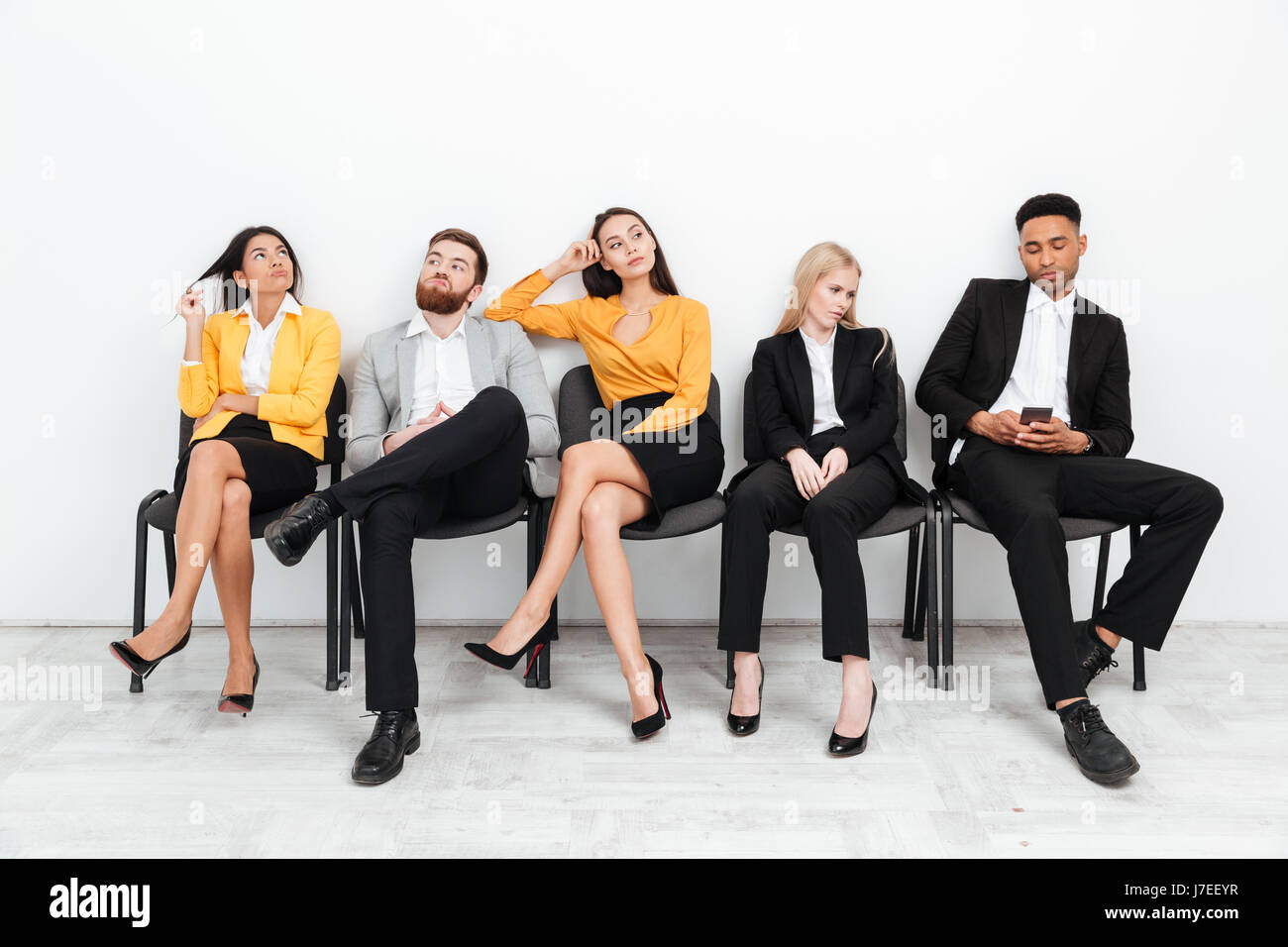 Photo of a group of tired colleagues sitting in office while looking ...