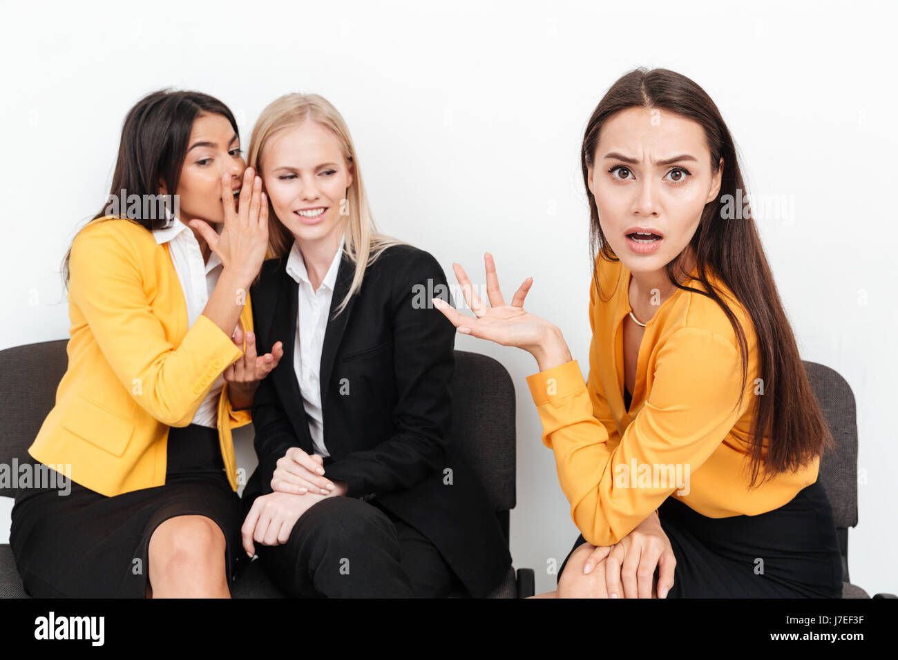 Picture of confused woman sitting near happy colleagues women in office ...
