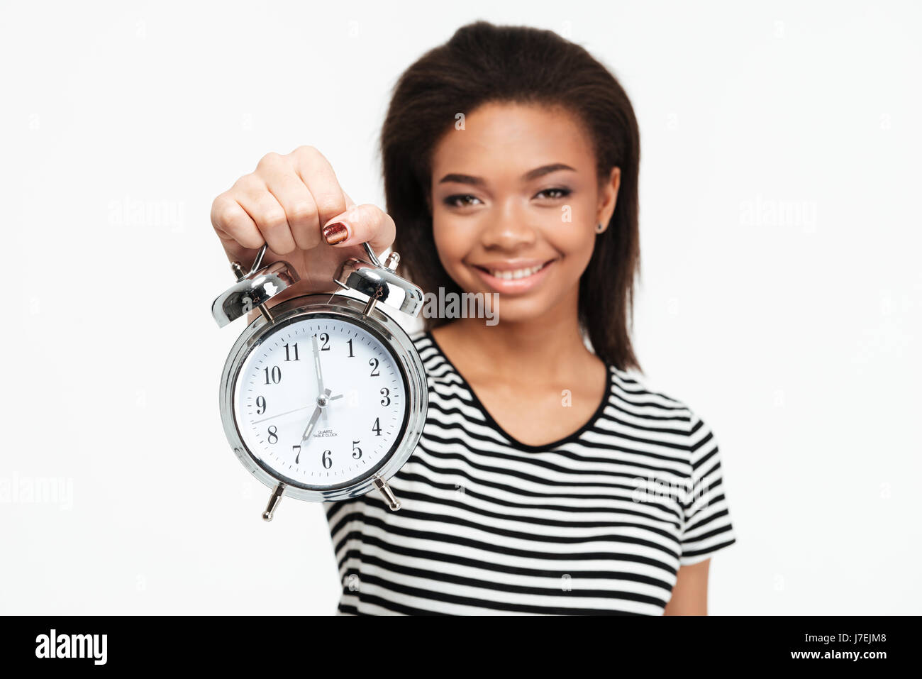 Portrait of a happy young african teen girl showing alarm clock ...