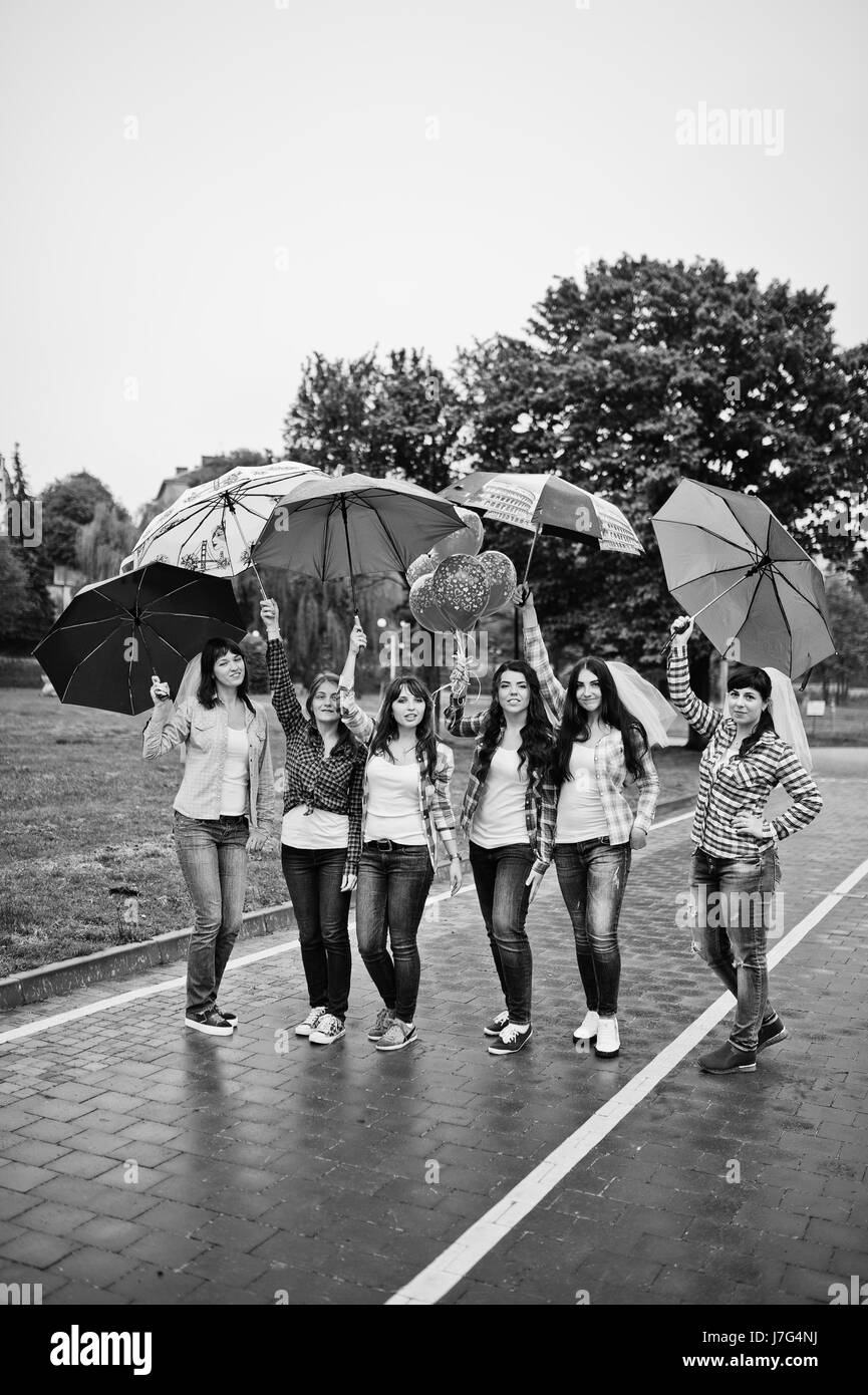 Group of six girls having fun at hen party, with umbrella under rain ...