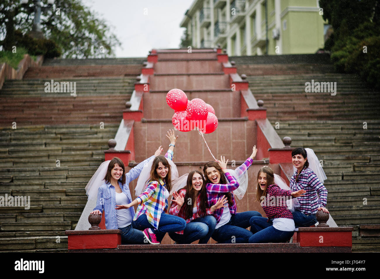 Group of six girls having fun at hen party, with balloons under rain at ...