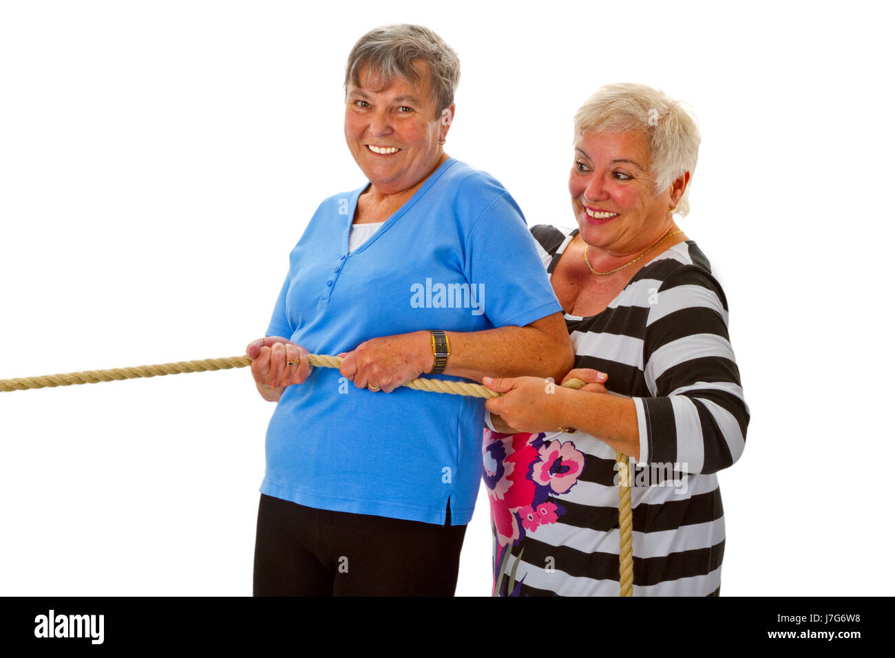 Two female seniors pulling on a rope - isolated on white background ...