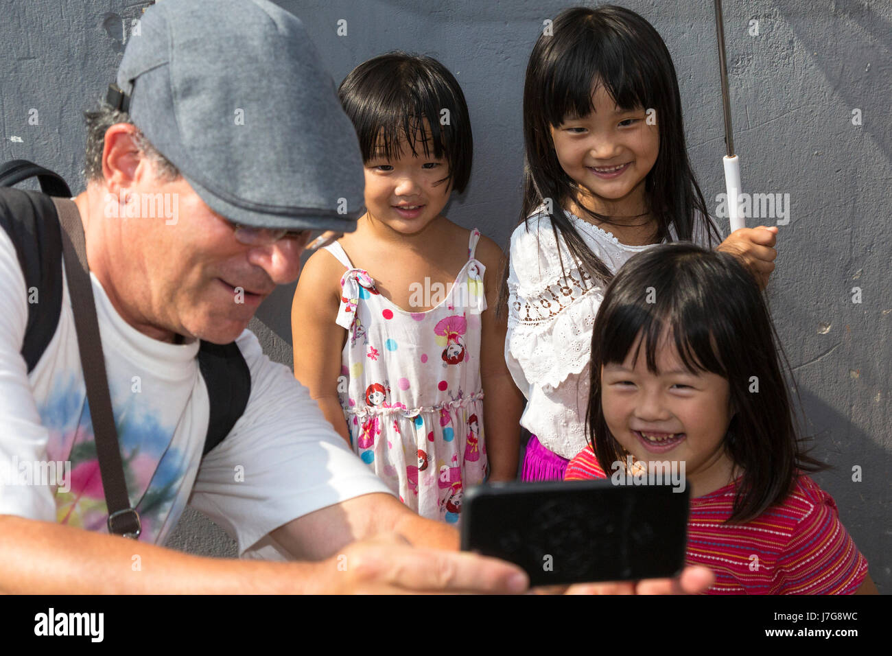 Photographer showing smiling Chinese children his pictures, Shanghai ...