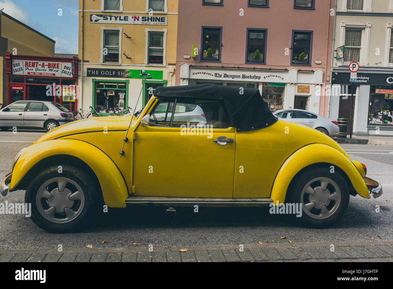 a convertible vintage yellow coloured volkswagen car parked on the road ...