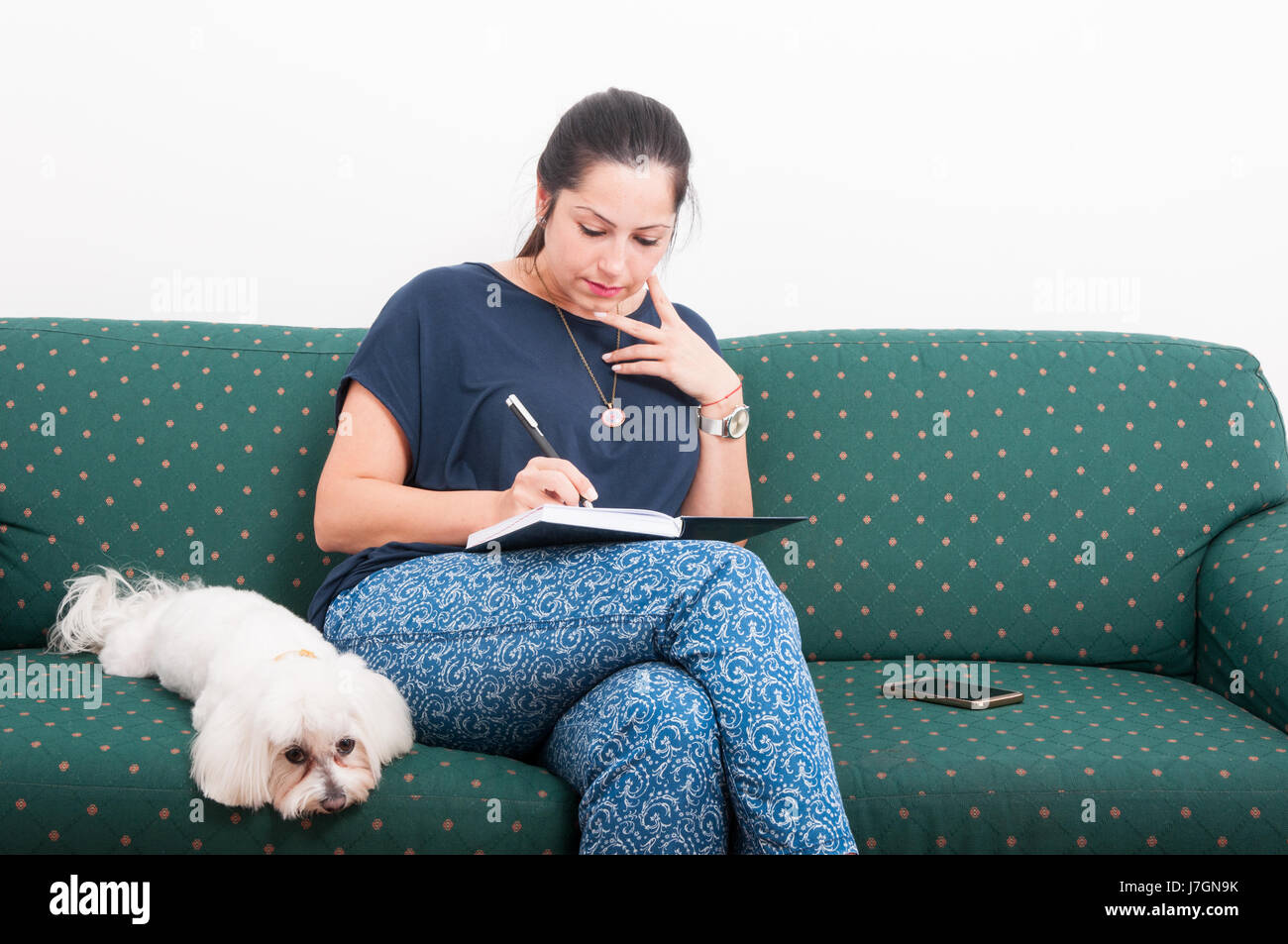 Young woman making notes in her journal and relaxing at home on the ...
