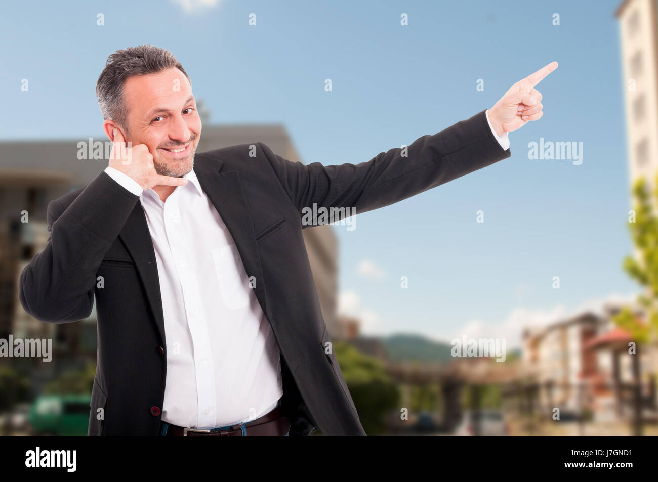 Handsome realtor outdoors pointing at something while doing a call sign ...