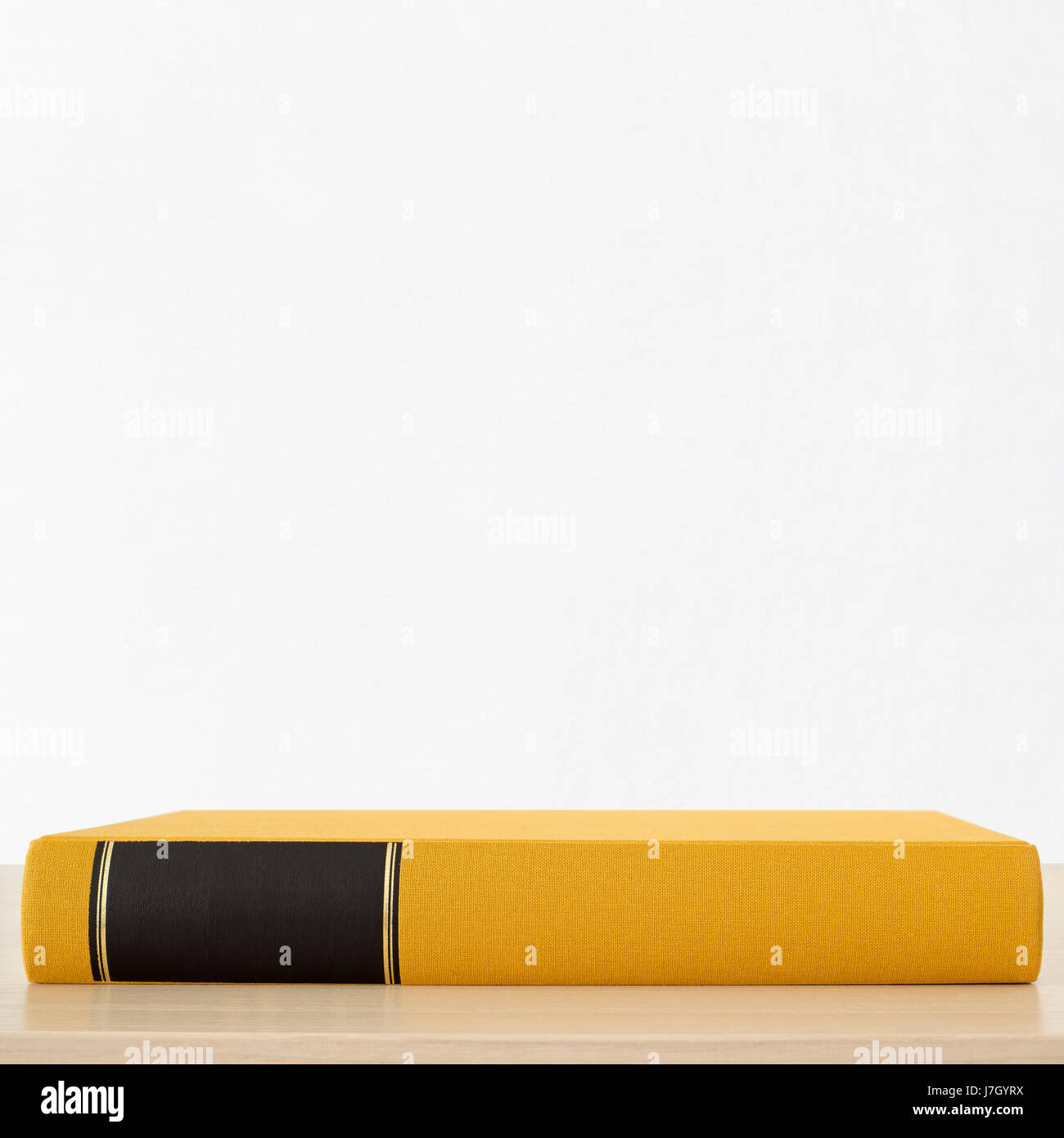 Yellow book with black frame on spine on the table Stock Photo - Alamy