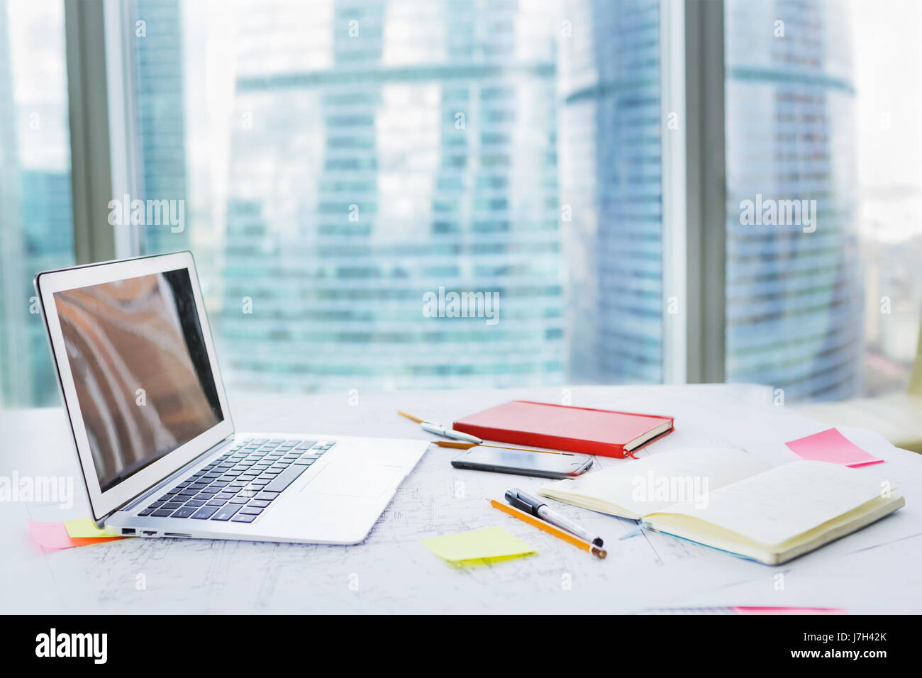 Side view of office workplace with laptop, notebook, smartphone on ...