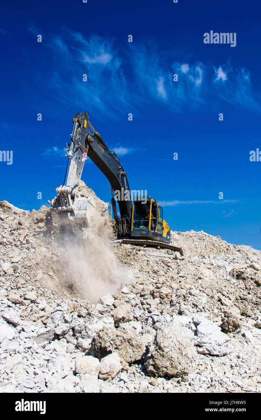 the excavator digging clay on blue sky background Stock Photo - Alamy
