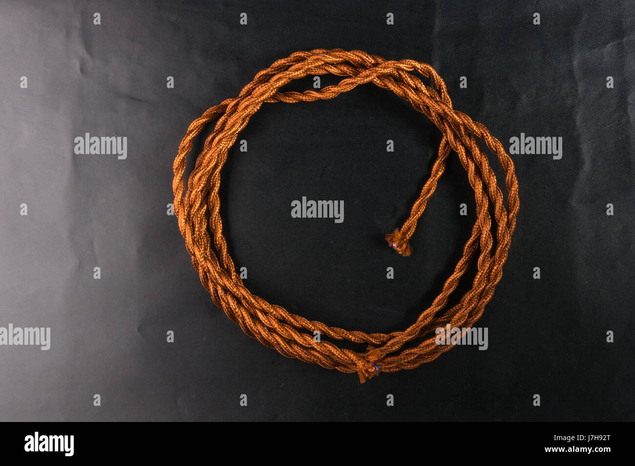 Electric cable in brown braid of fabric in retro style on black ...