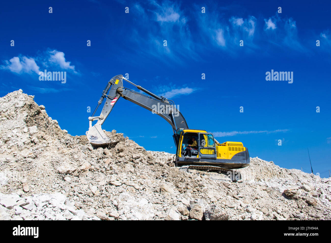 the excavator digging clay on blue sky background Stock Photo - Alamy