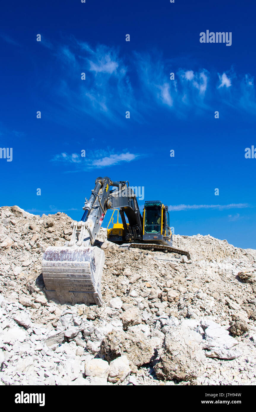 the excavator digging clay on blue sky background Stock Photo - Alamy
