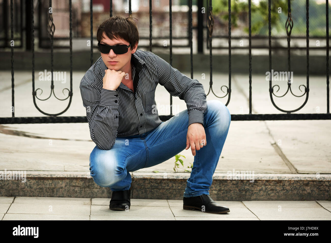 Young man at the cast iron fence Stock Photo - Alamy