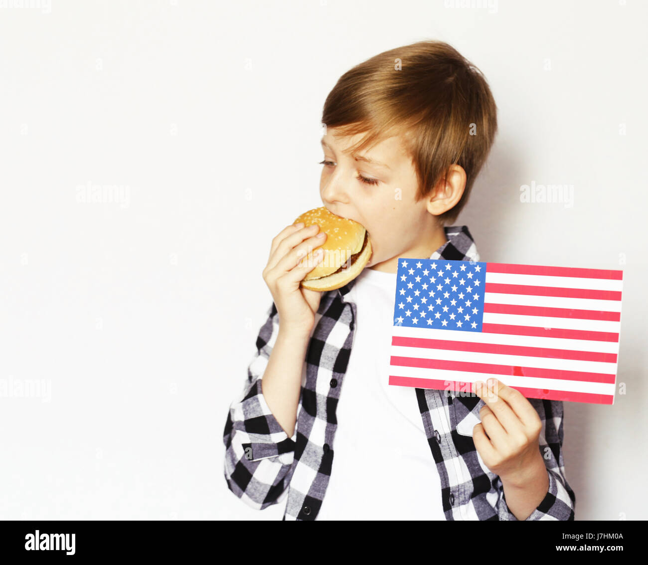 Cute blonde boy eating cheeseburger - American food Stock Photo - Alamy