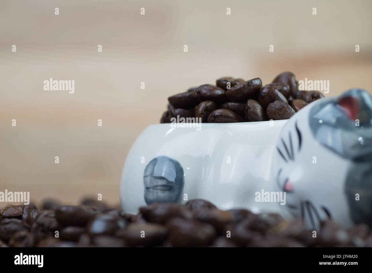 Coffee beans in cat ceramic pot on wood background with selective focus ...