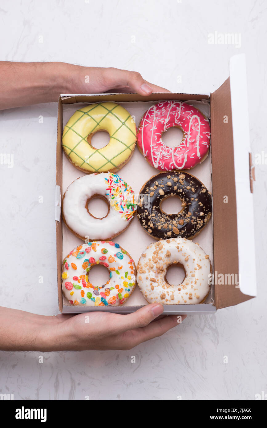 Hand holding colorful round donuts in the box Stock Photo - Alamy