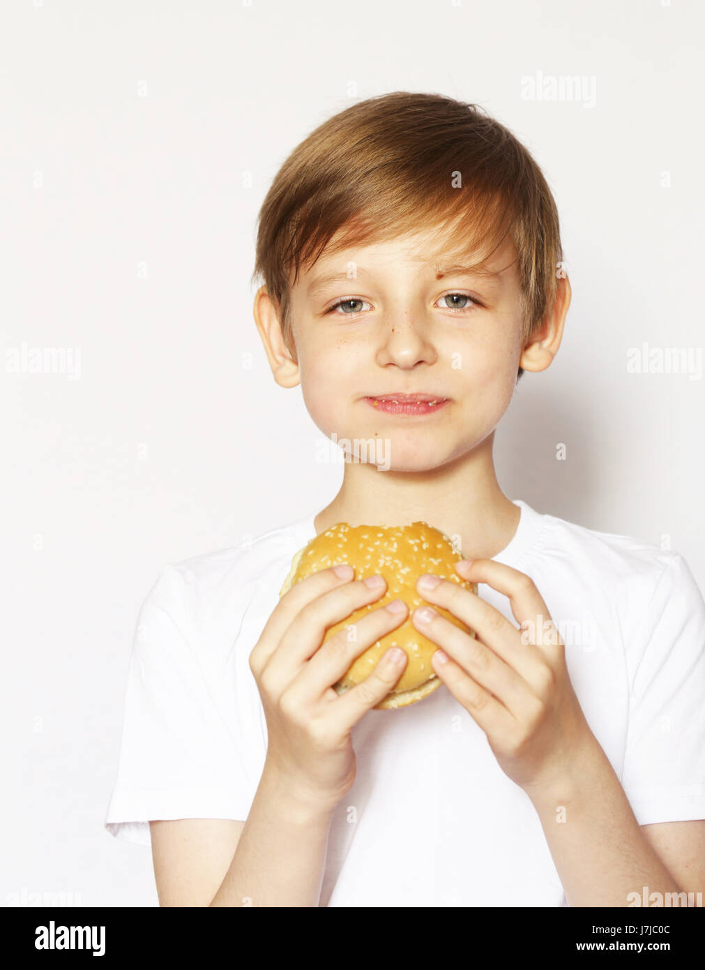 Cute blonde boy eating cheeseburger - American food Stock Photo - Alamy