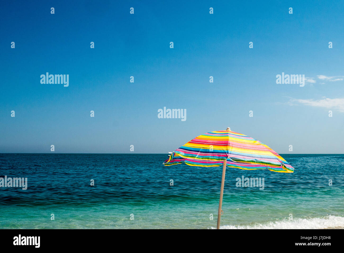 rainbow beach umbrella isolated on sea background, Mediterranean sea ...