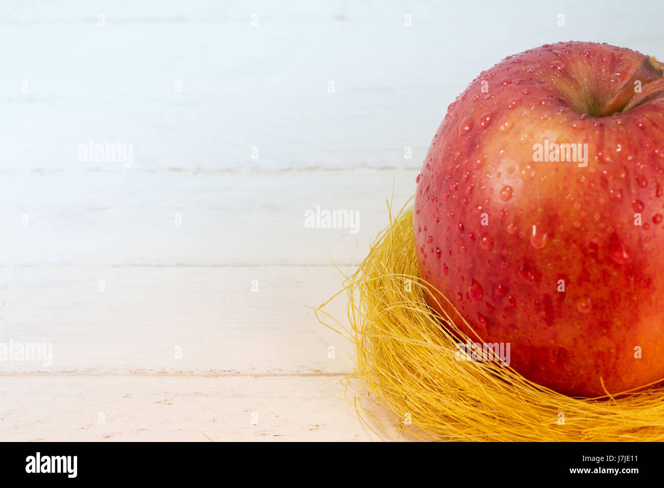 Fresh apple in golden nest on white wood background Stock Photo - Alamy