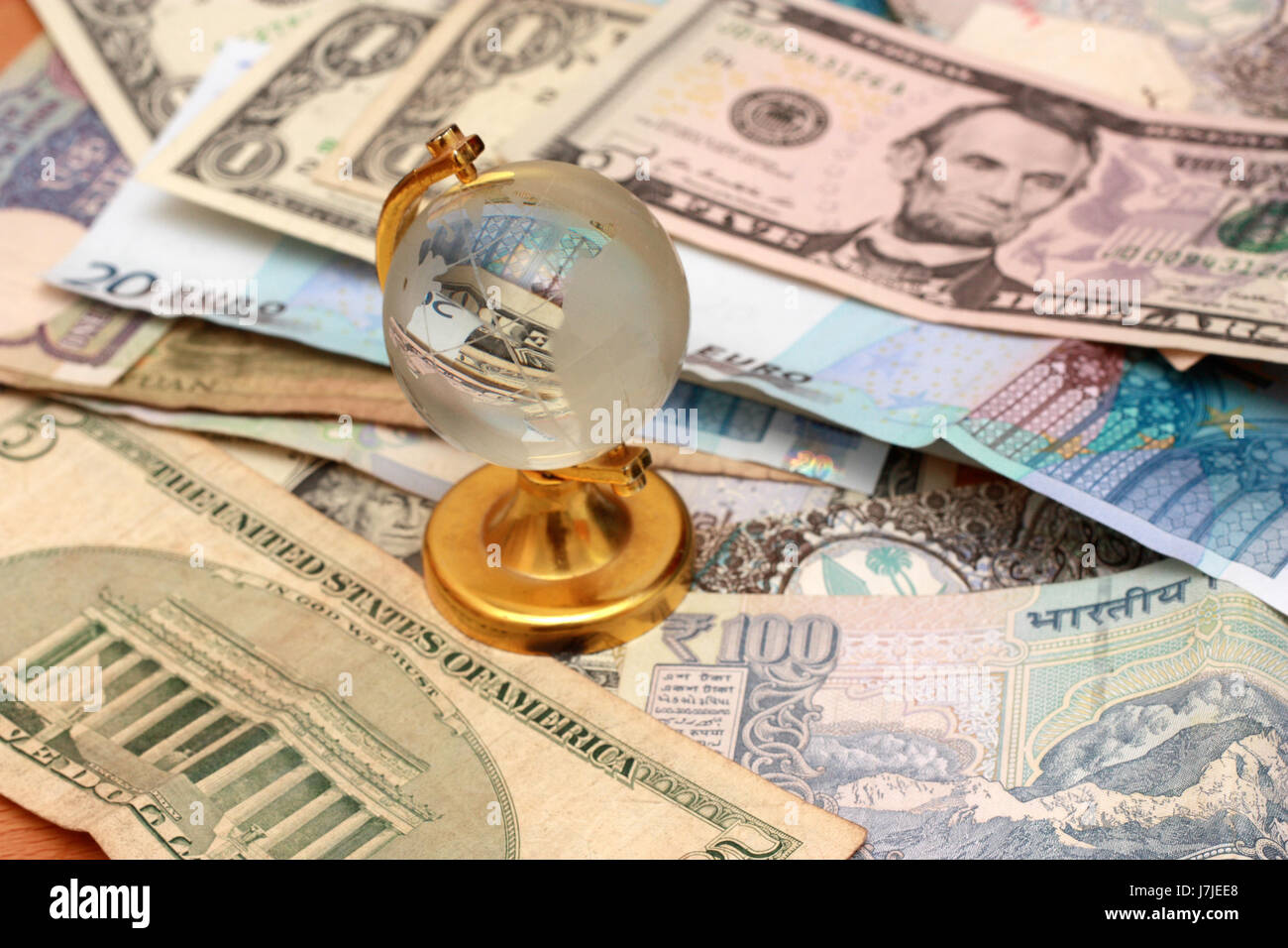 The image shows a glass globe with currencies of various countries such ...