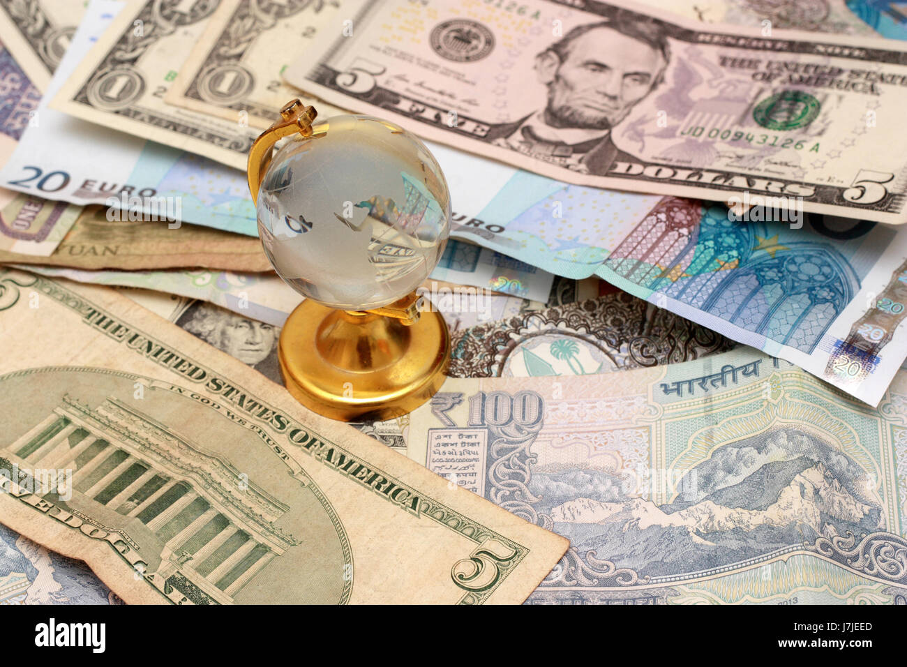 The image shows a glass globe with currencies of various countries such ...