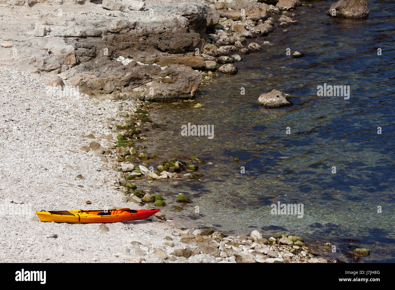 Orange kayak on pebbly beach of sea coast at sun summer day Stock Photo ...