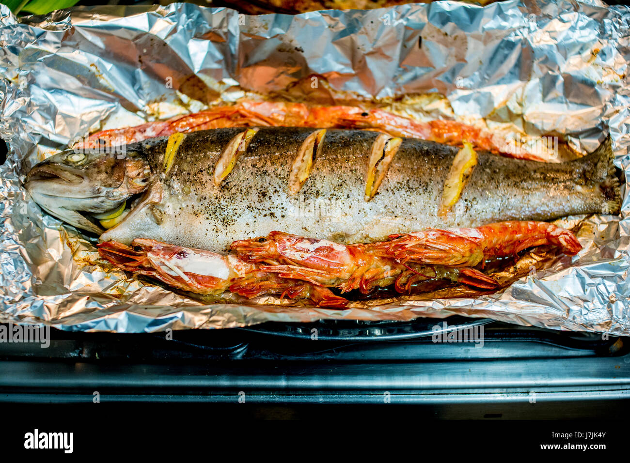 Fish ready to get toasted along with lemon, onion, garlic,olive oil ...