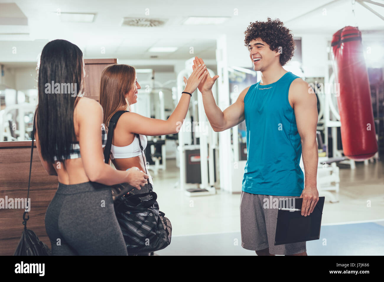 Two happiness female friends greetings with instructor at the gym Stock ...