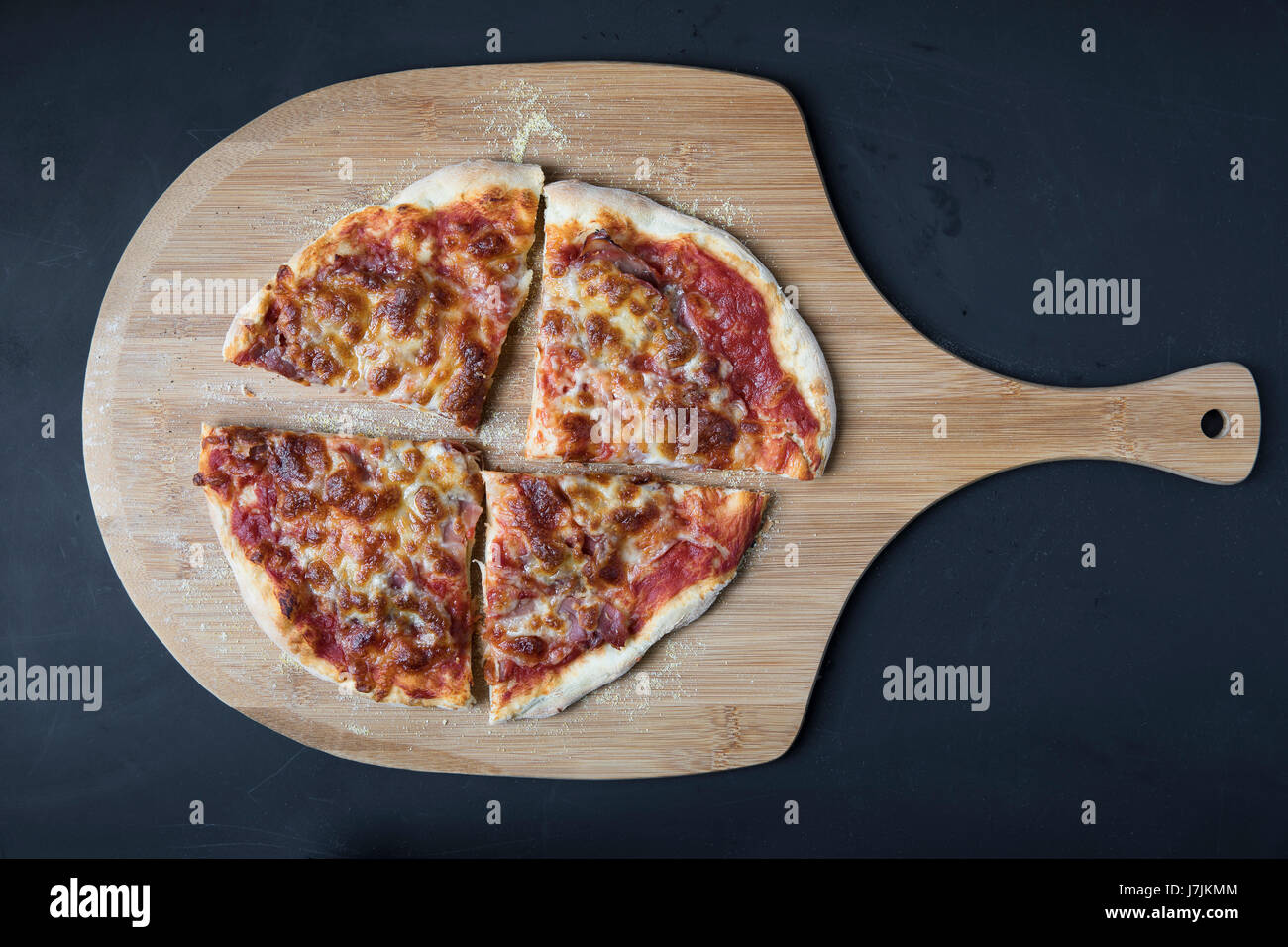 Fresh cheese and ham pizza slices on pizza peel Stock Photo - Alamy