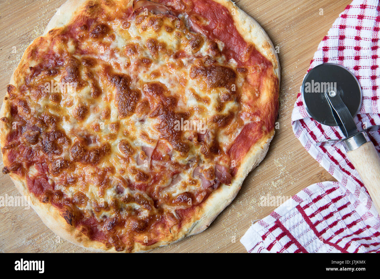 Whole homemade cheese and ham pizza with pizza wheel Stock Photo - Alamy