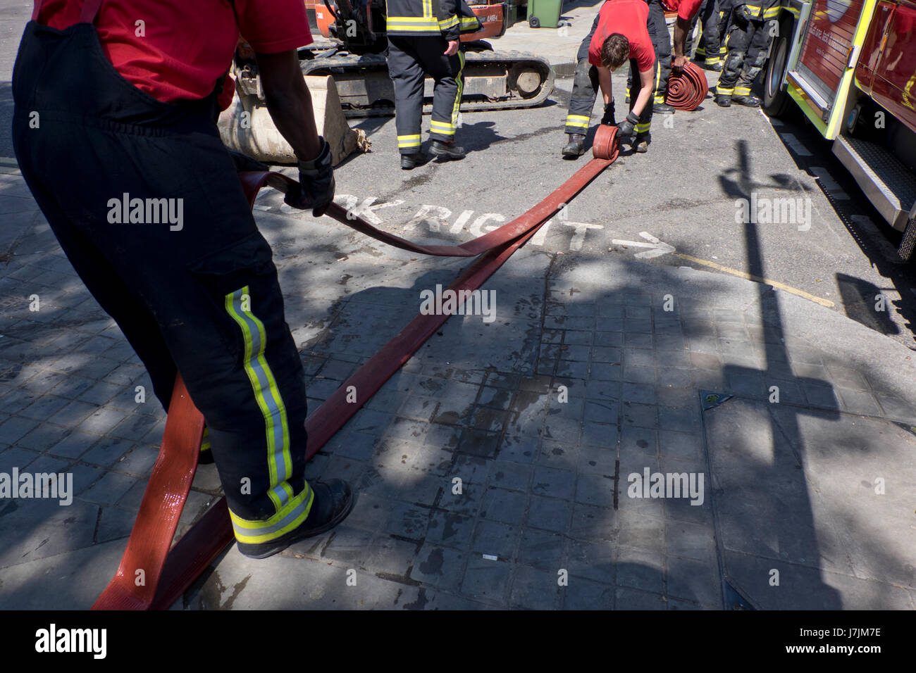 Fire Brigade officers clearing equipment after fighting a fire in a ...