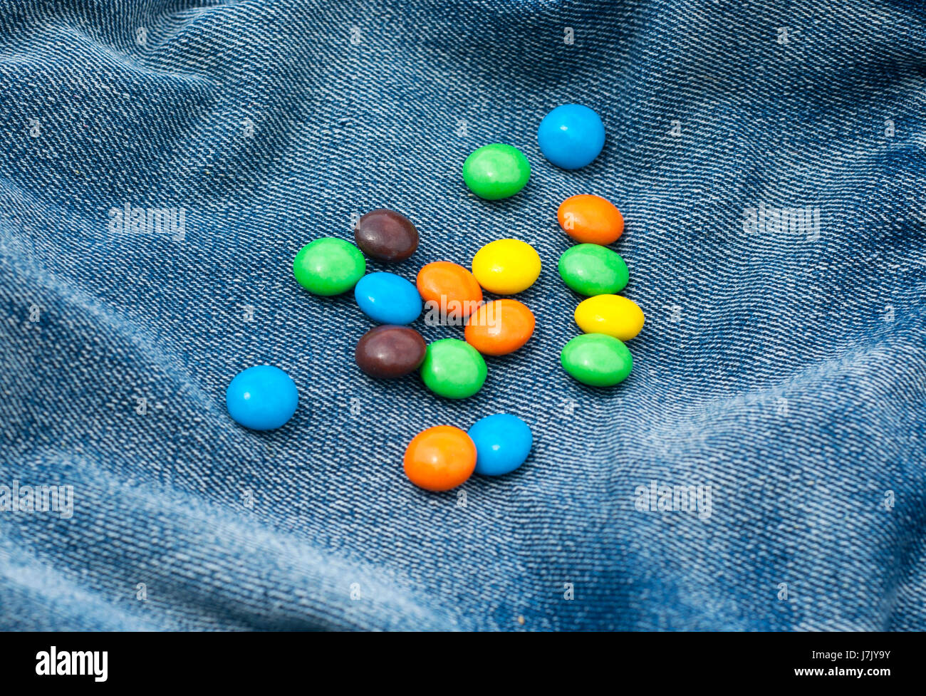 Colorful of chocolate little candies isolated on jeans blue background ...