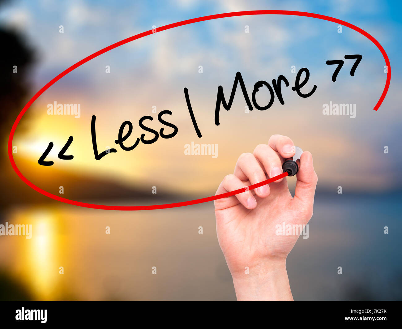 Man Hand writing Less - More with black marker on visual screen ...