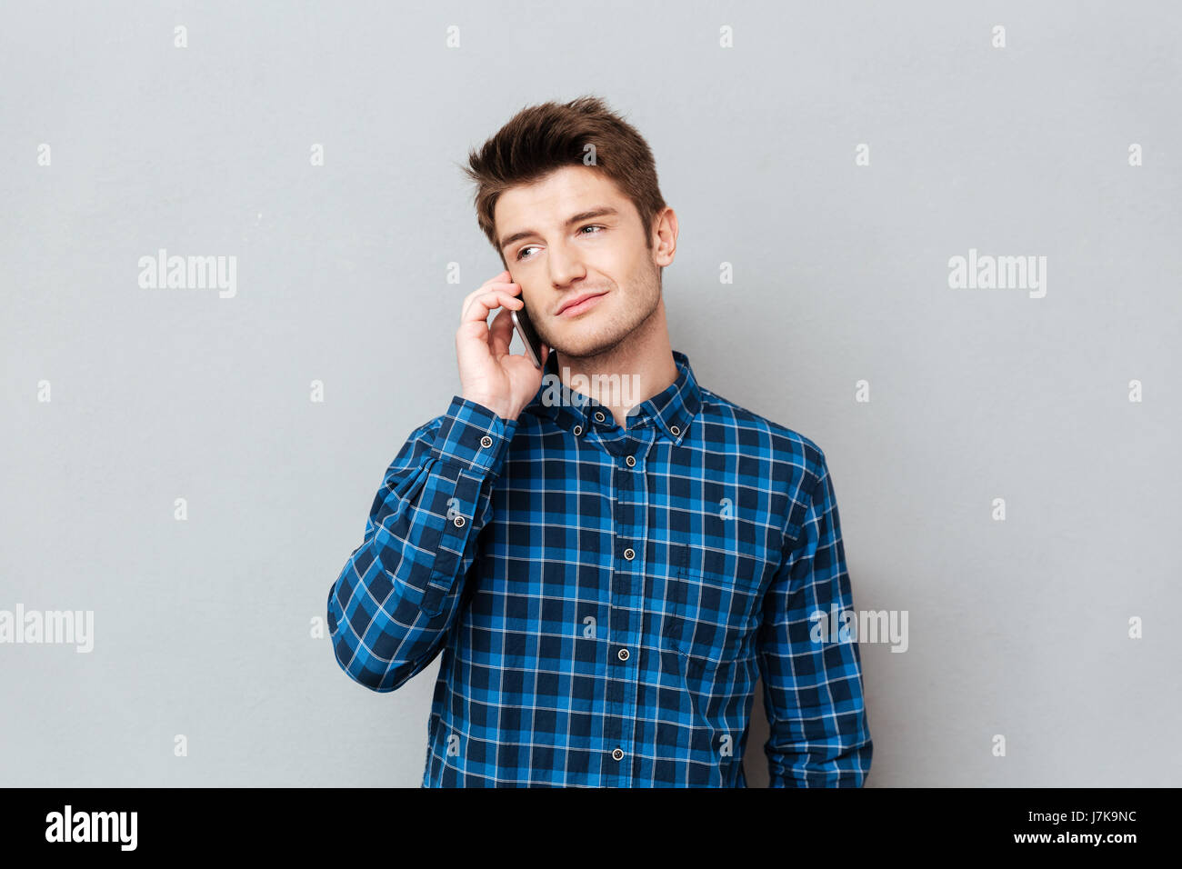 Picture of handsome young man standing over grey wall and talking by ...